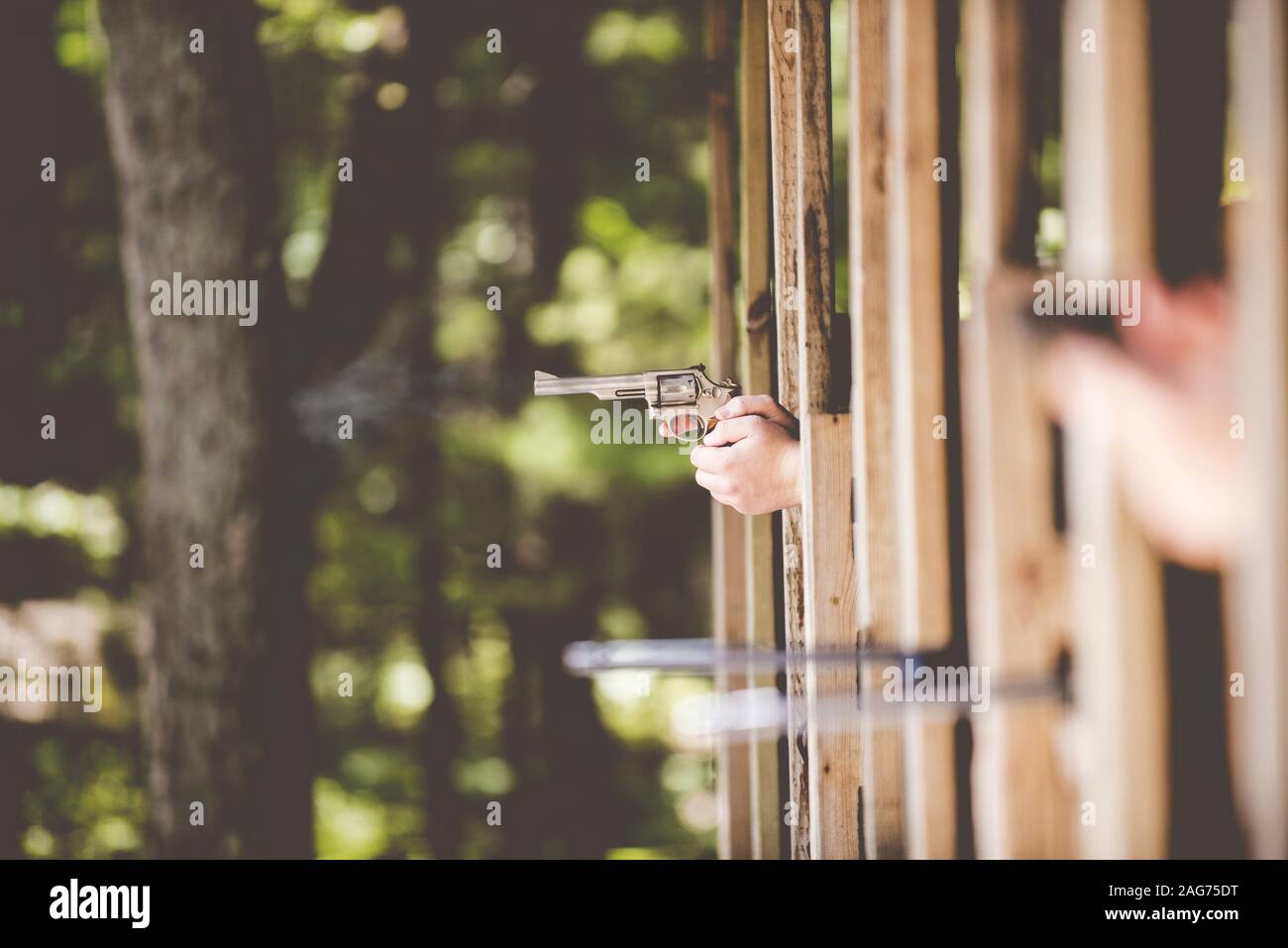 Selective focus shot of a person shooting a revolver with a blurred ...