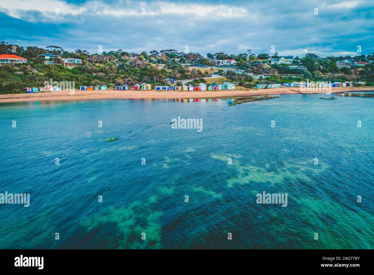 Shallow bay water reflecting colorful beach huts on ocean coastline in ...