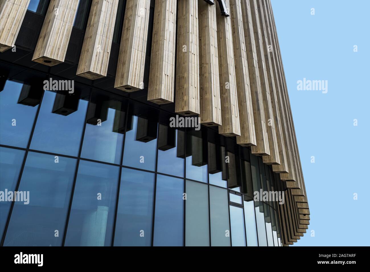 Low angle shot of a modern glass building covered with a stone curtain ...