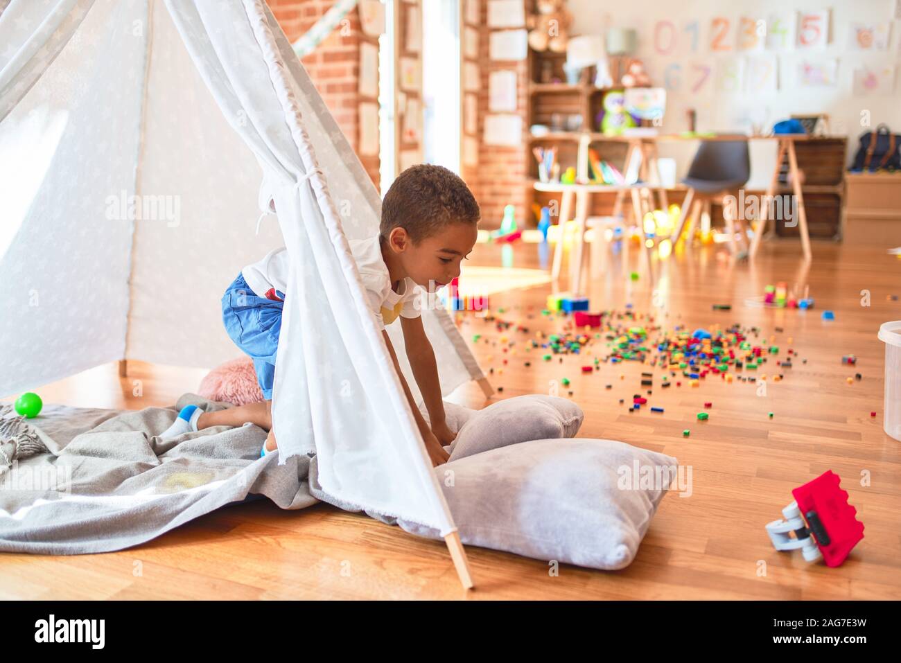 Beautiful african american toddler playing inside tipi smiling at ...