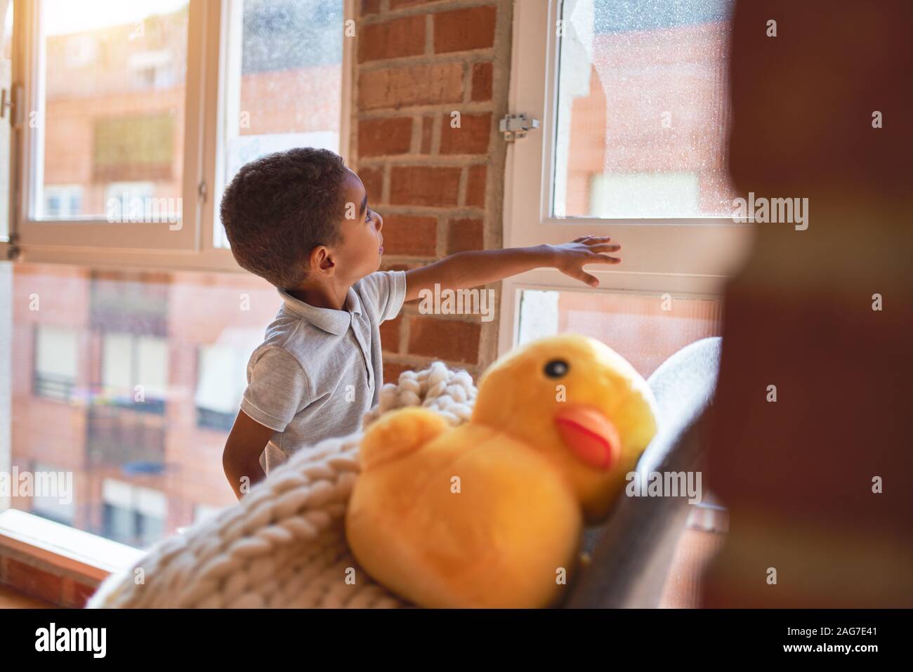 Beautiful african american toddler standing looking through the window ...