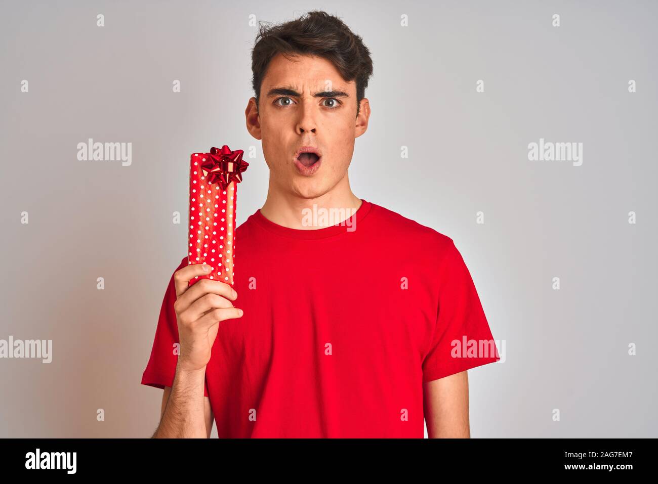 Teenager boy holding birthday gift over isolated background scared in ...