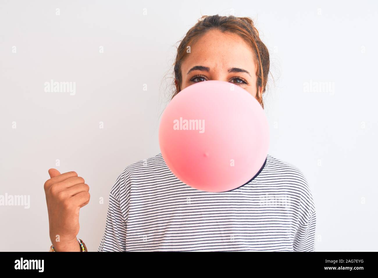 Young redhead woman chewing gum and blowing hair bubble over white ...