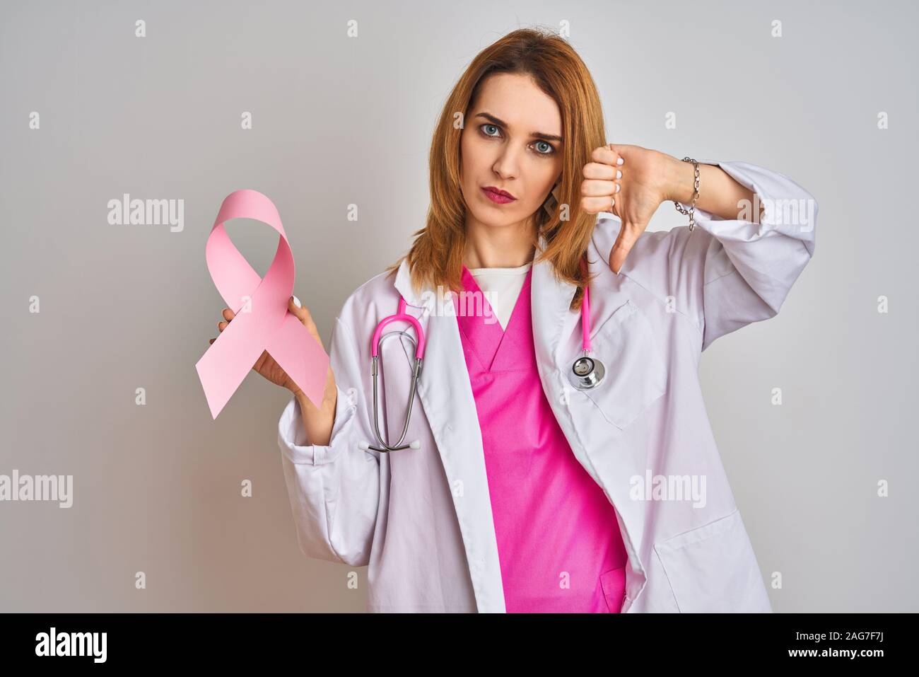 Redhead caucasian doctor woman holding pink cancer ribbon over isolated ...