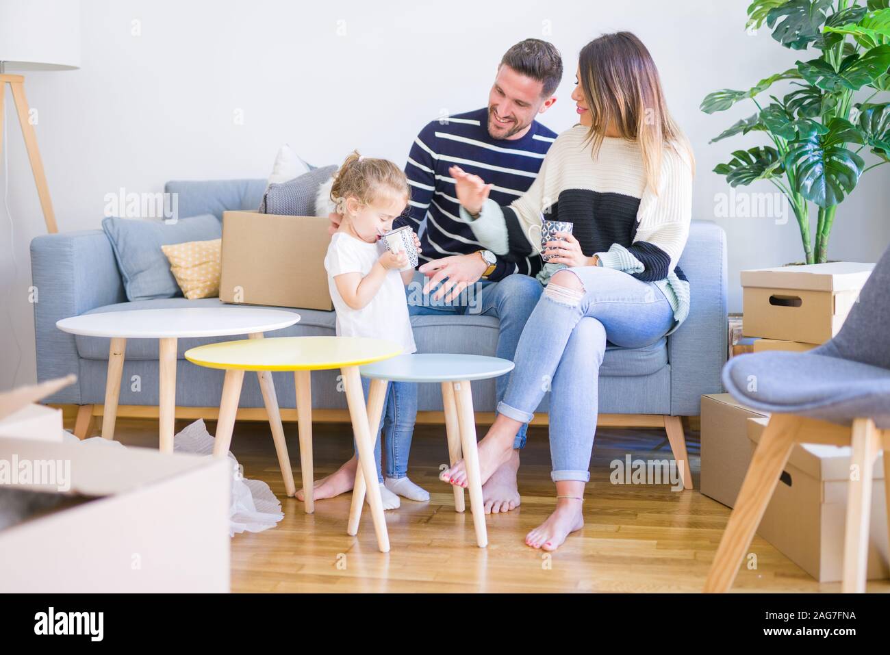 Beautiful family, parents sitting on the sofa drinking coffee looking ...