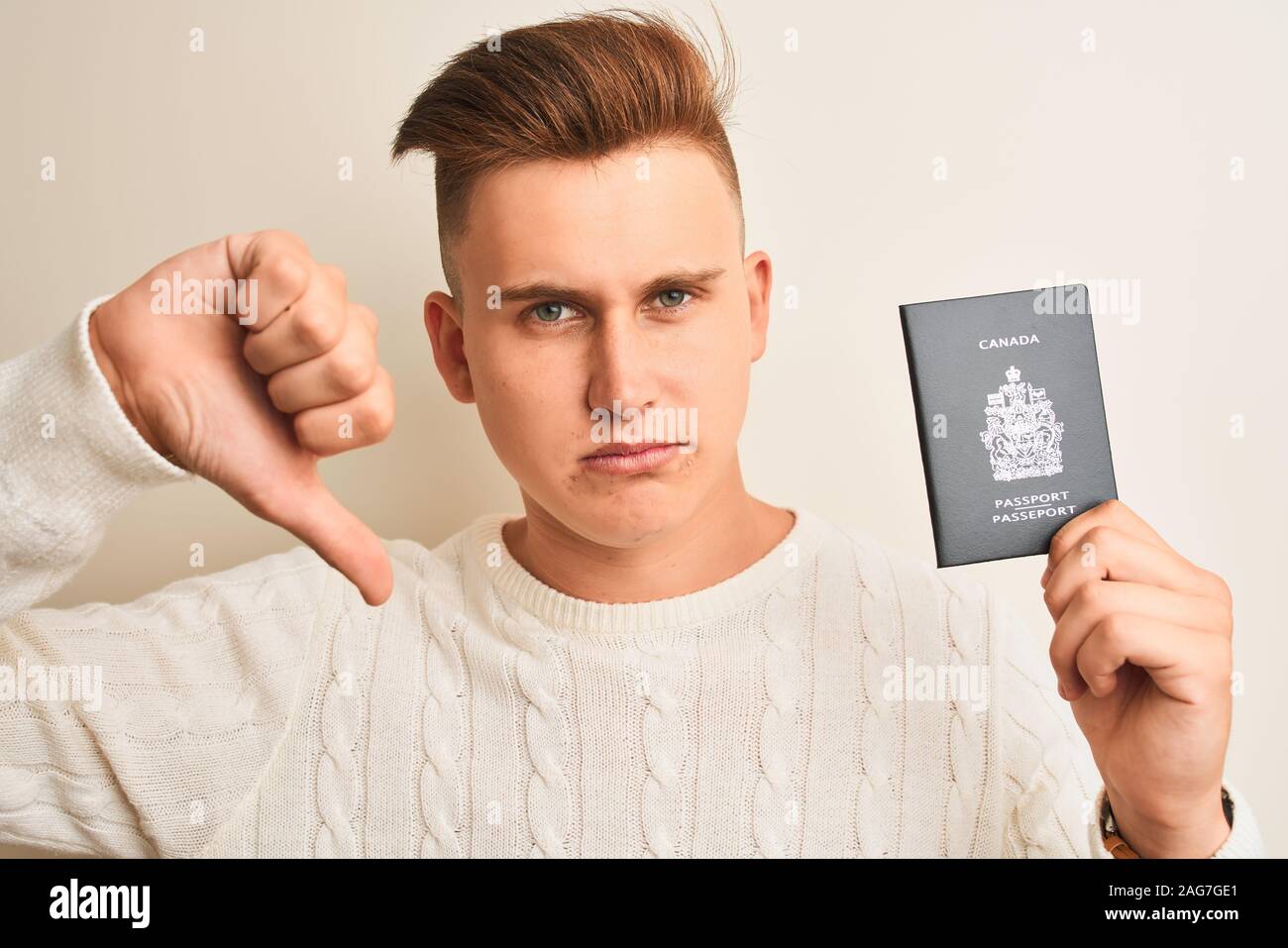 Young handsome man holding Canada Canadian passport over isolated white ...