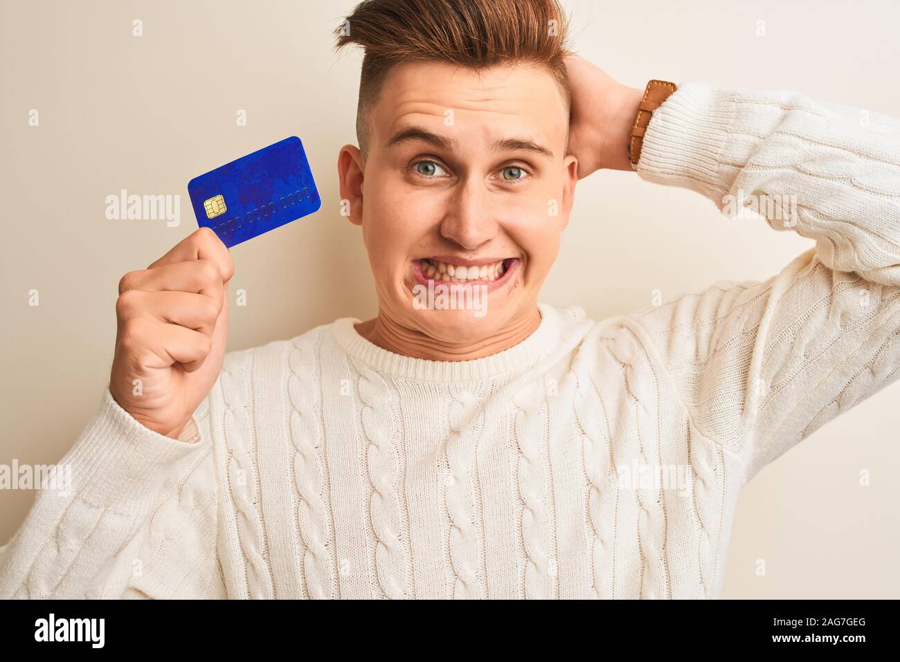 Young handsome man holding credit card over isolated white background ...