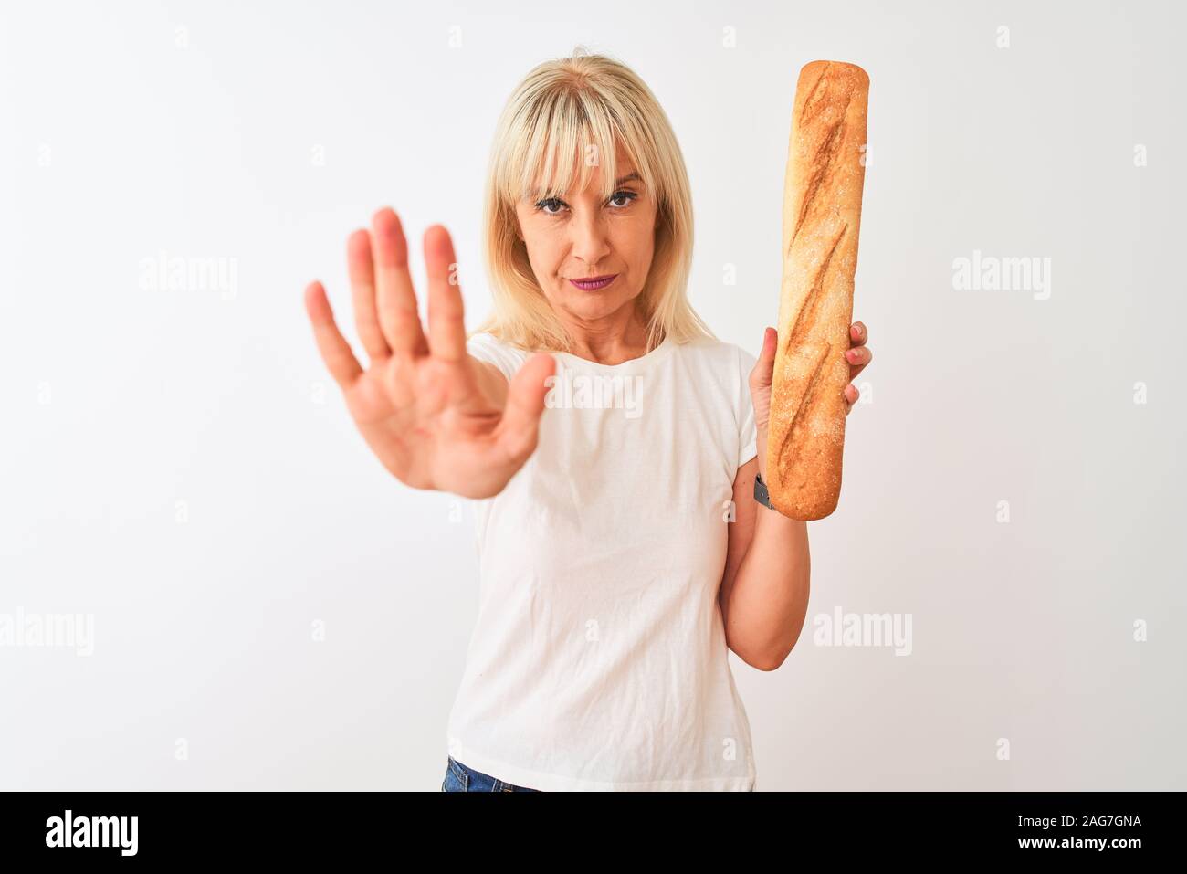 Middle age baker woman holding bread standing over isolated white ...