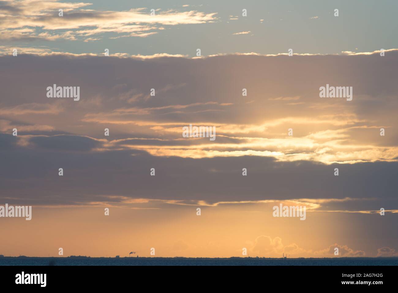 Breathtaking scenery of the sun setting behind the clouds creating the ...