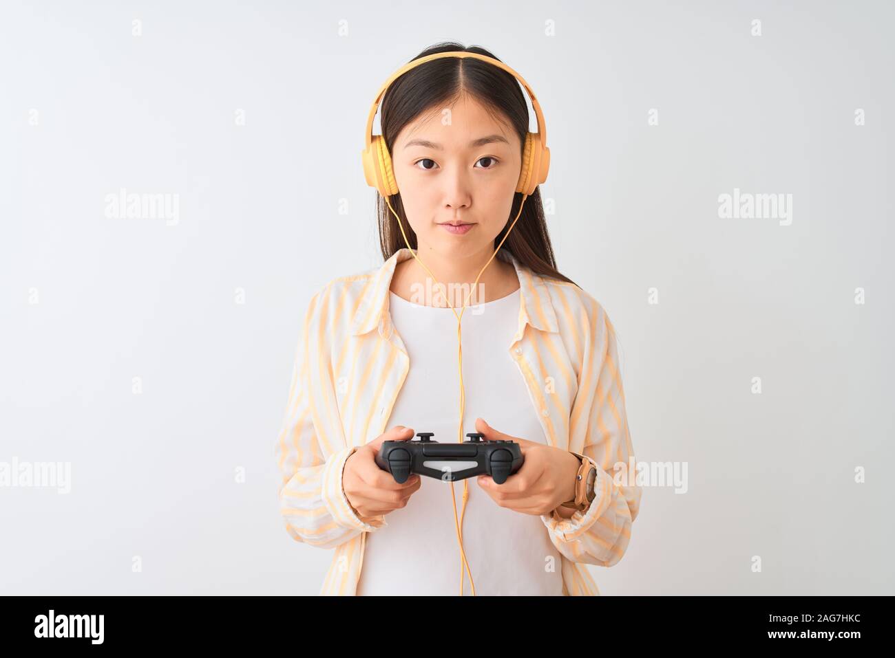 Chinese gamer woman playing video game using headphones over isolated ...