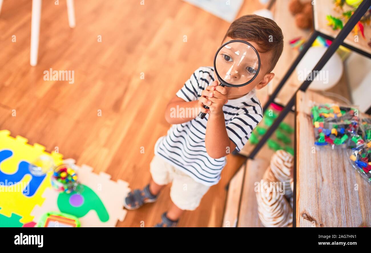 Beautiful toddler boy using magnifying glass at kindergarten Stock ...