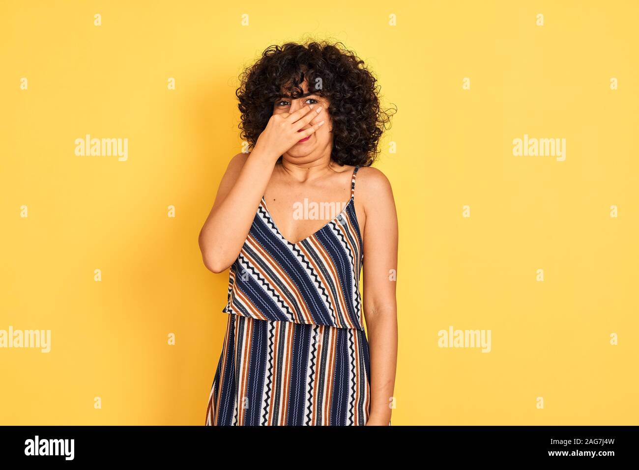 Arab woman with curly hair wearing striped colorful dress over isolated ...