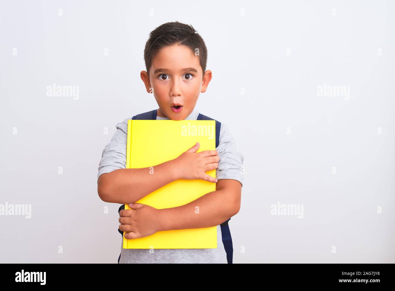Beautiful student kid boy wearing backpack holding book over isolated ...