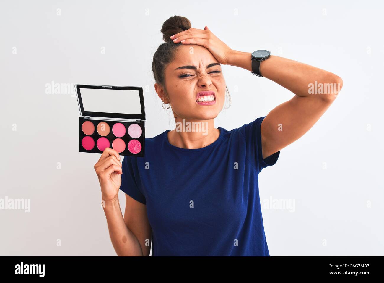 Young beautiful woman holding makeup standing over isolated white ...