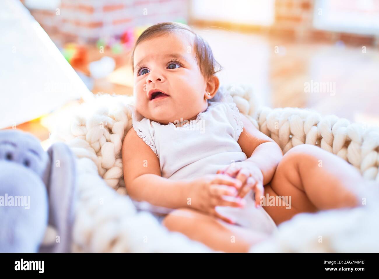 Beautiful infant happy at kindergarten around colorful toys lying ...