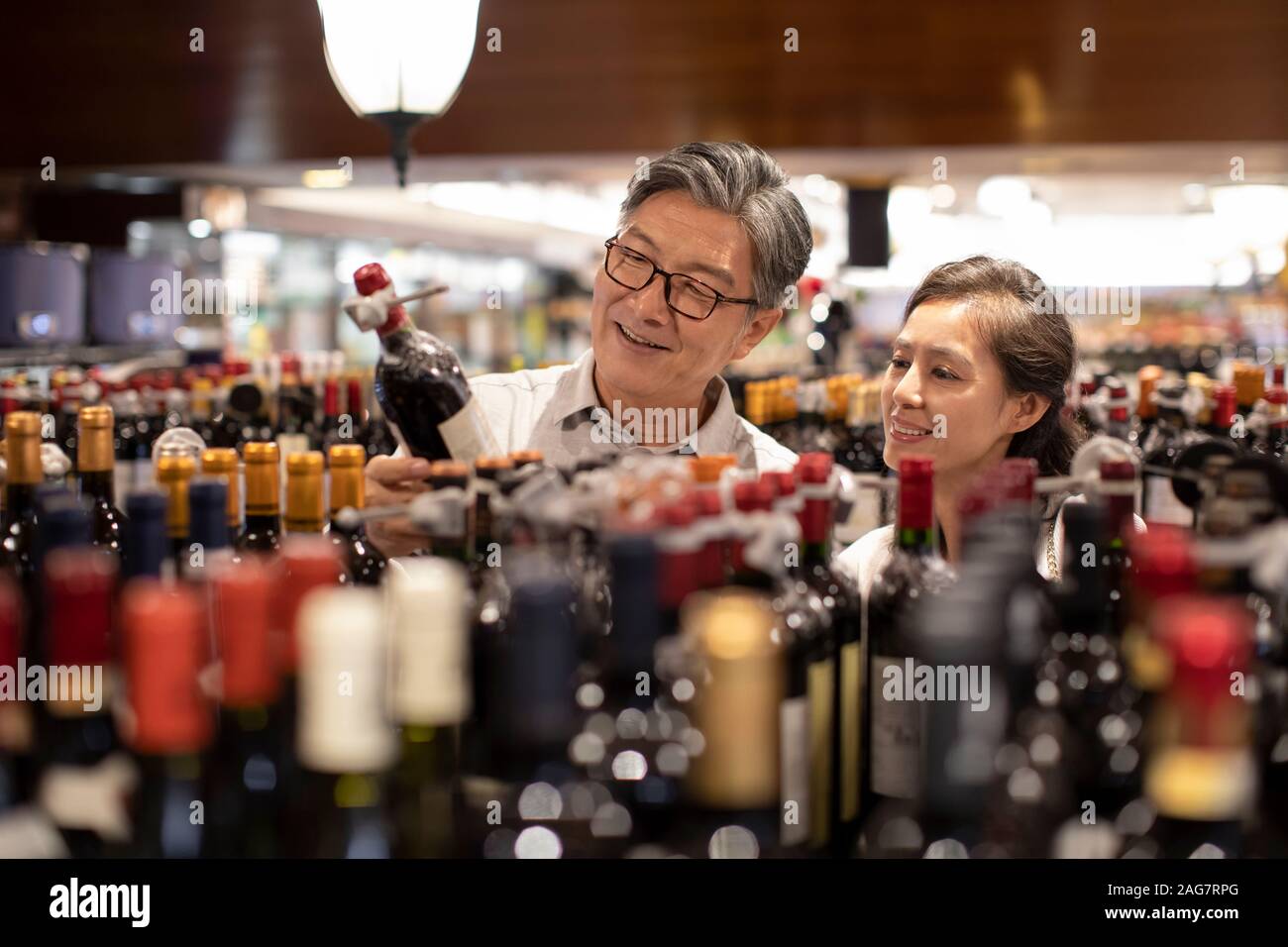 Mature Chinese couple choosing wine in supermarket Stock Photo - Alamy