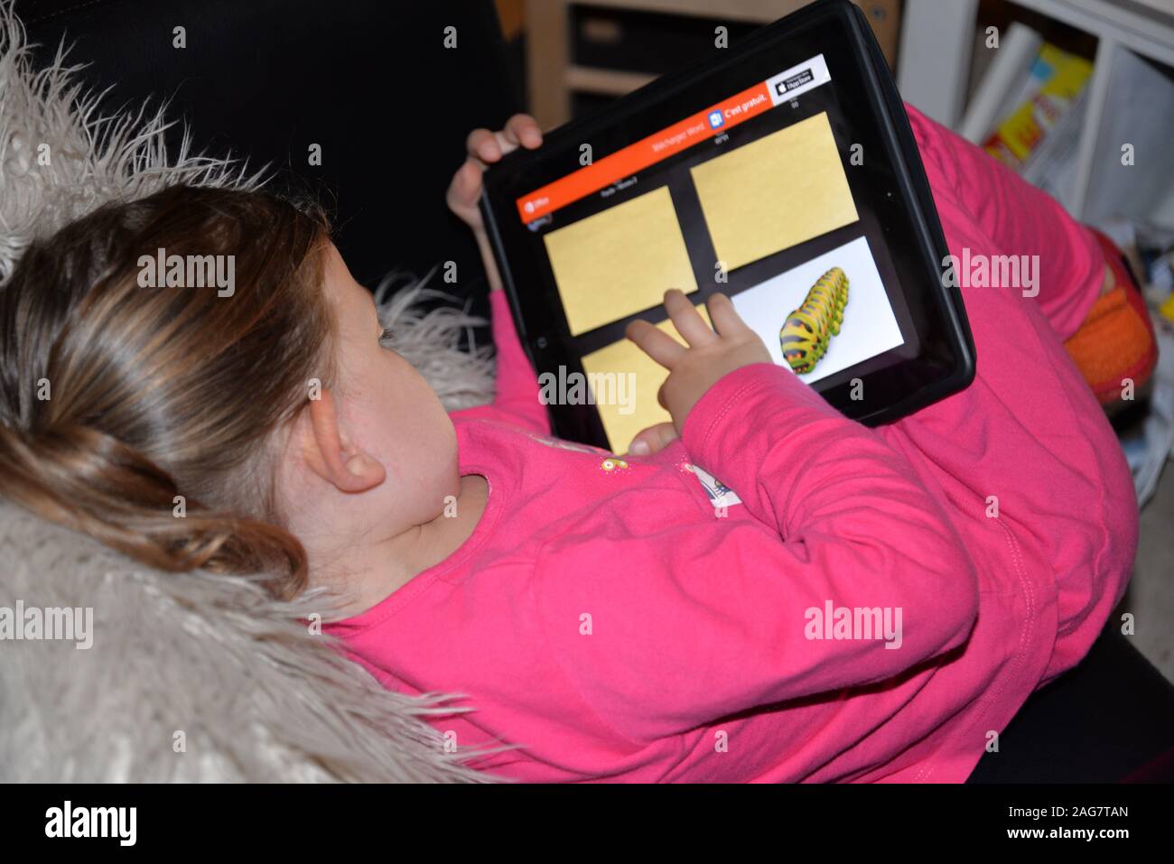 Concentred little girl in red pajamas playing with her tablet Stock ...