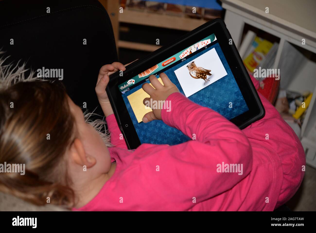 Concentred little girl in red pajamas playing with her tablet Stock ...