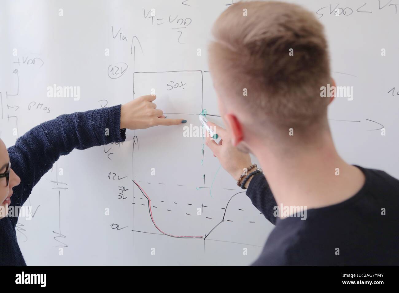 Two young college male and female students writting on the chalkboard ...