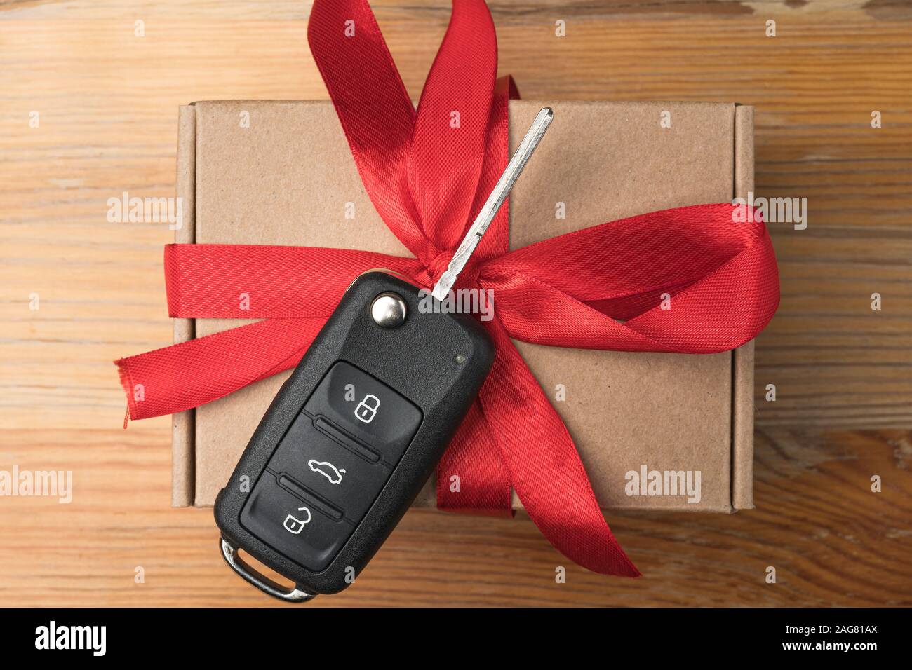 Car key on a paper box with red bow on natural wooden table background ...
