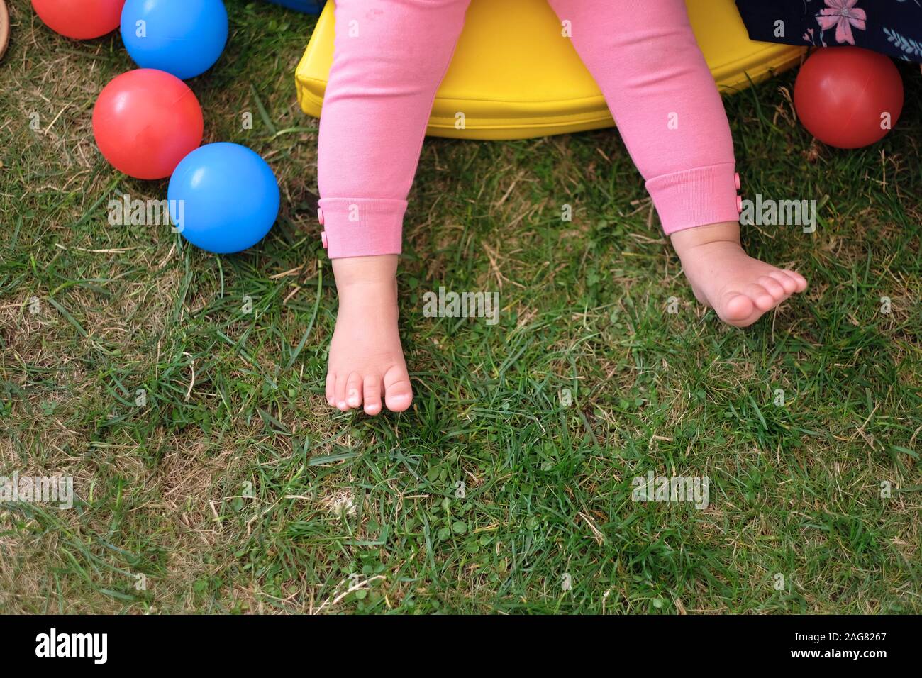 Baby's legs on the green lawn grass among the red and blue balls Stock ...