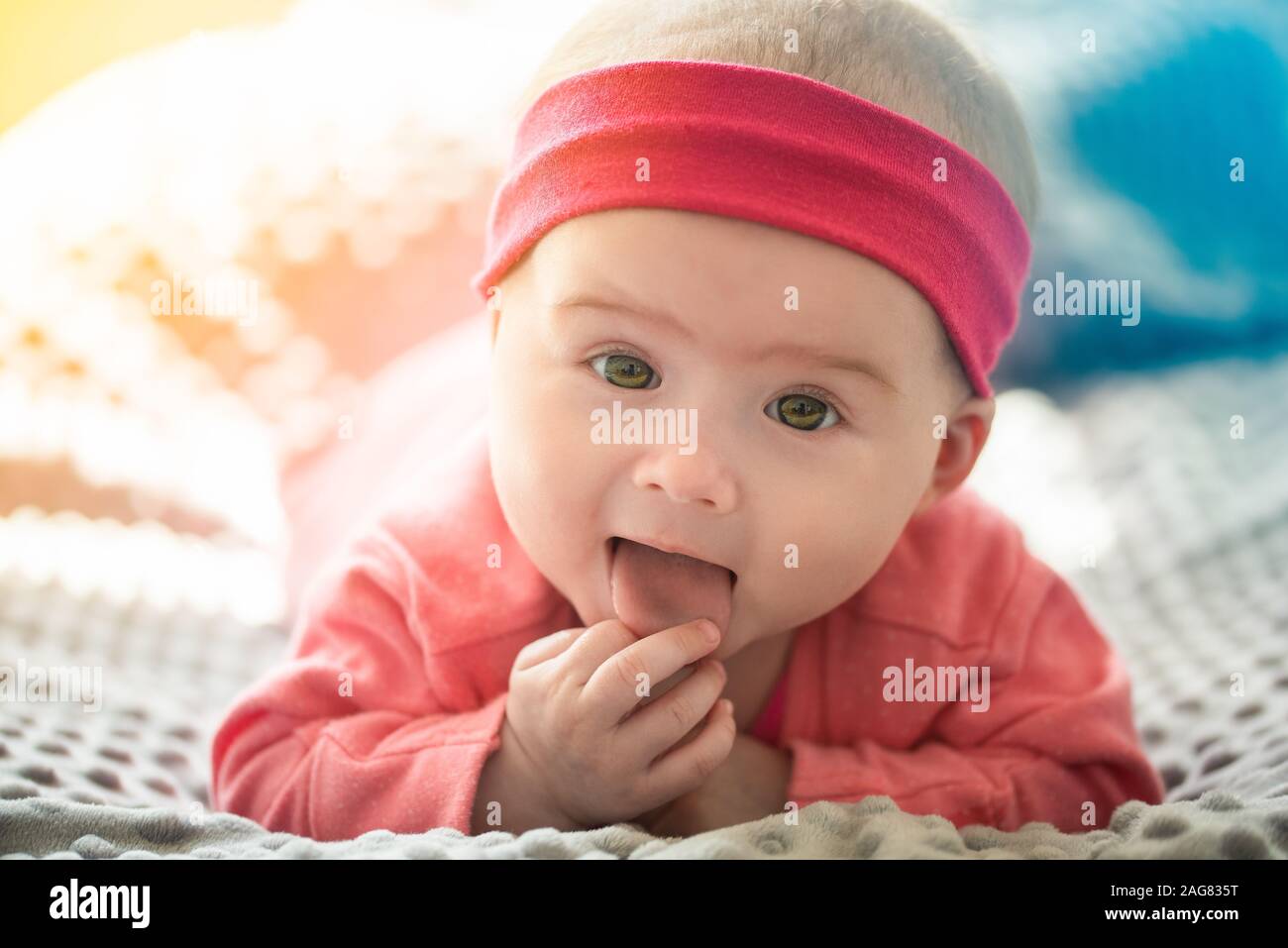Cute five months old Baby girl infant on a bed on her belly with head ...
