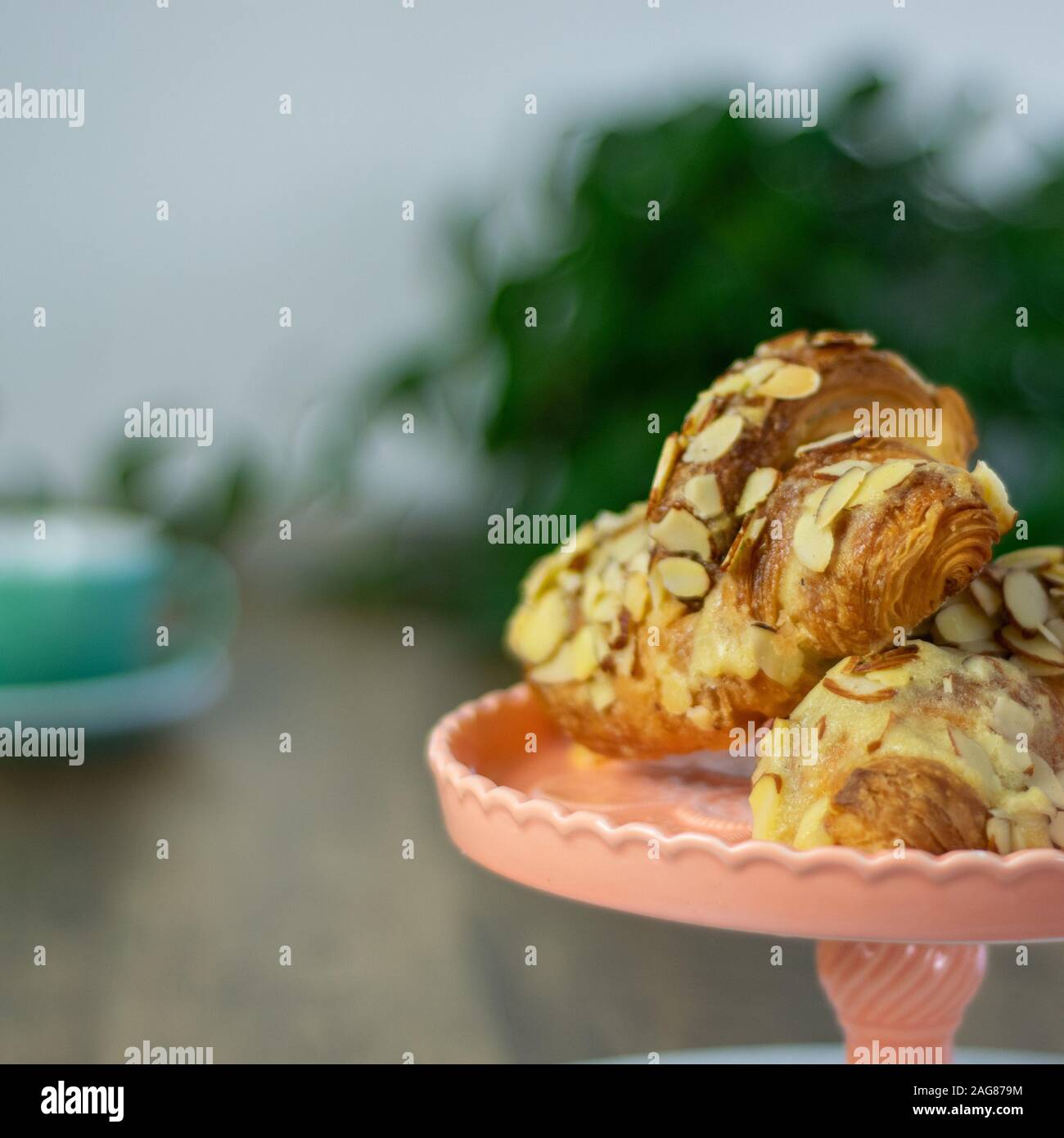 Almond croissant on cake stand with greenery and coffee Stock Photo - Alamy