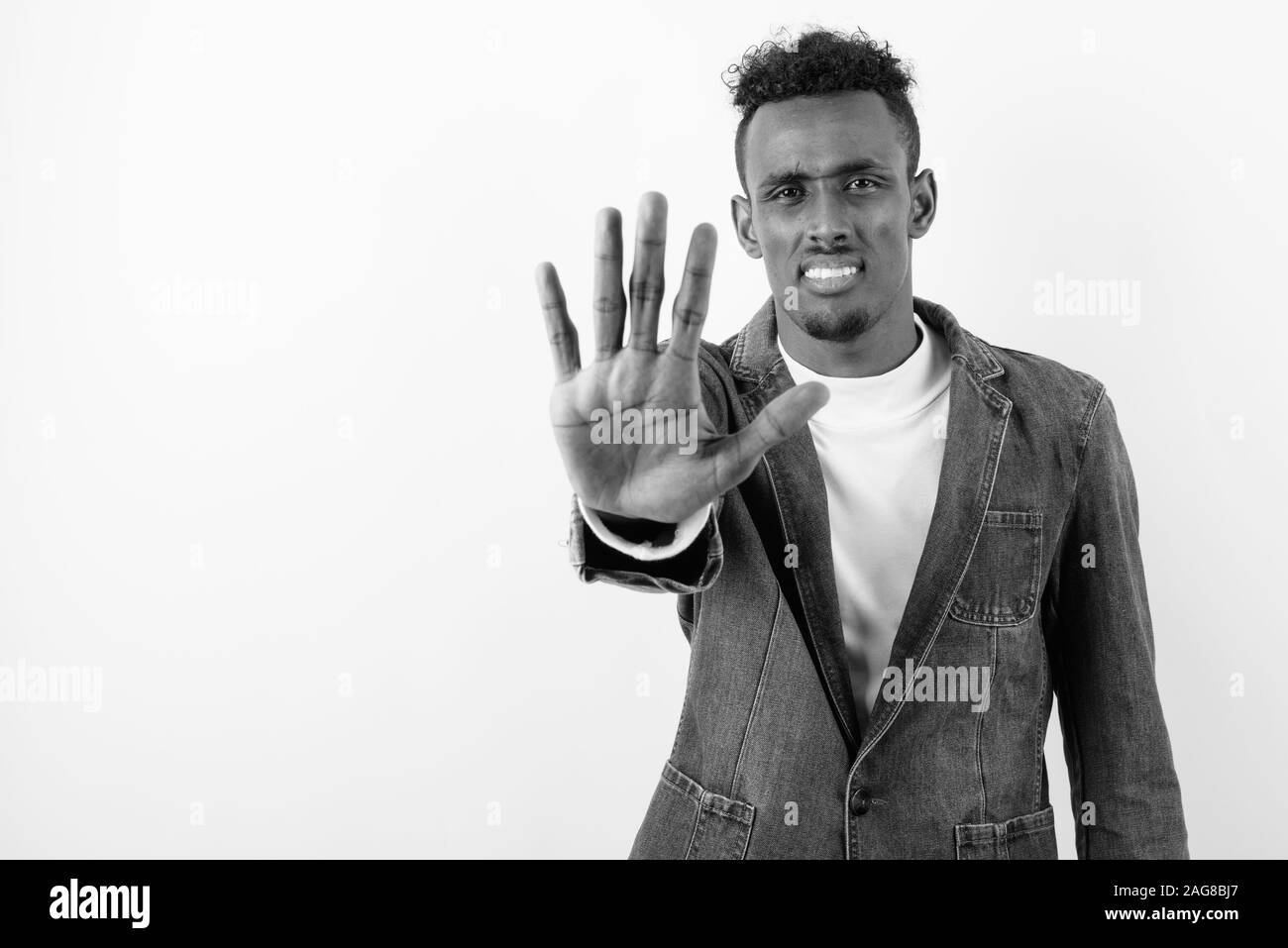 Young bearded African man wearing denim jacket against white background ...