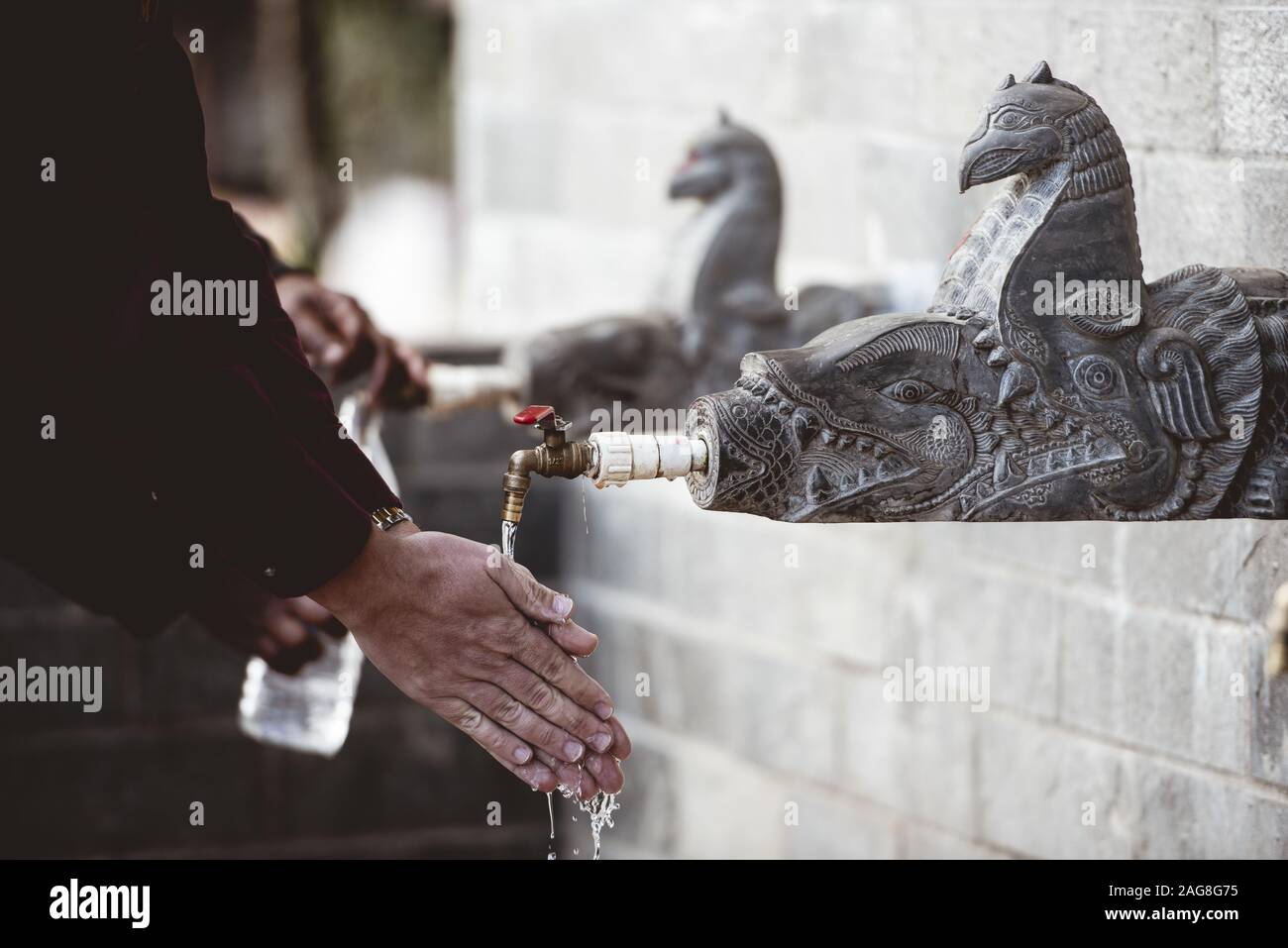 Closeup shot of a person washing hands with a blurred background at a ...