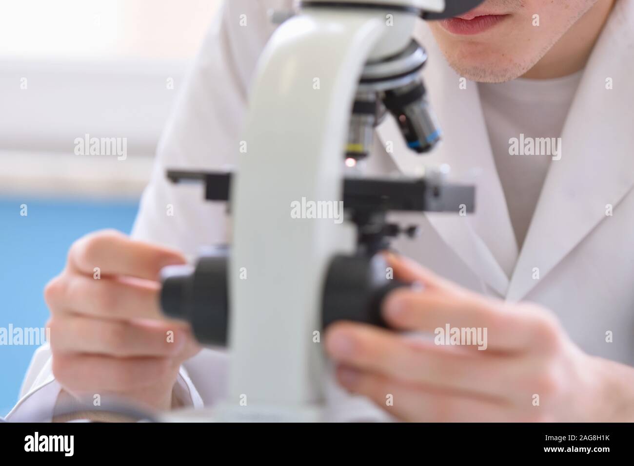 Young male scientist looking through a microscope in a laboratory doing ...