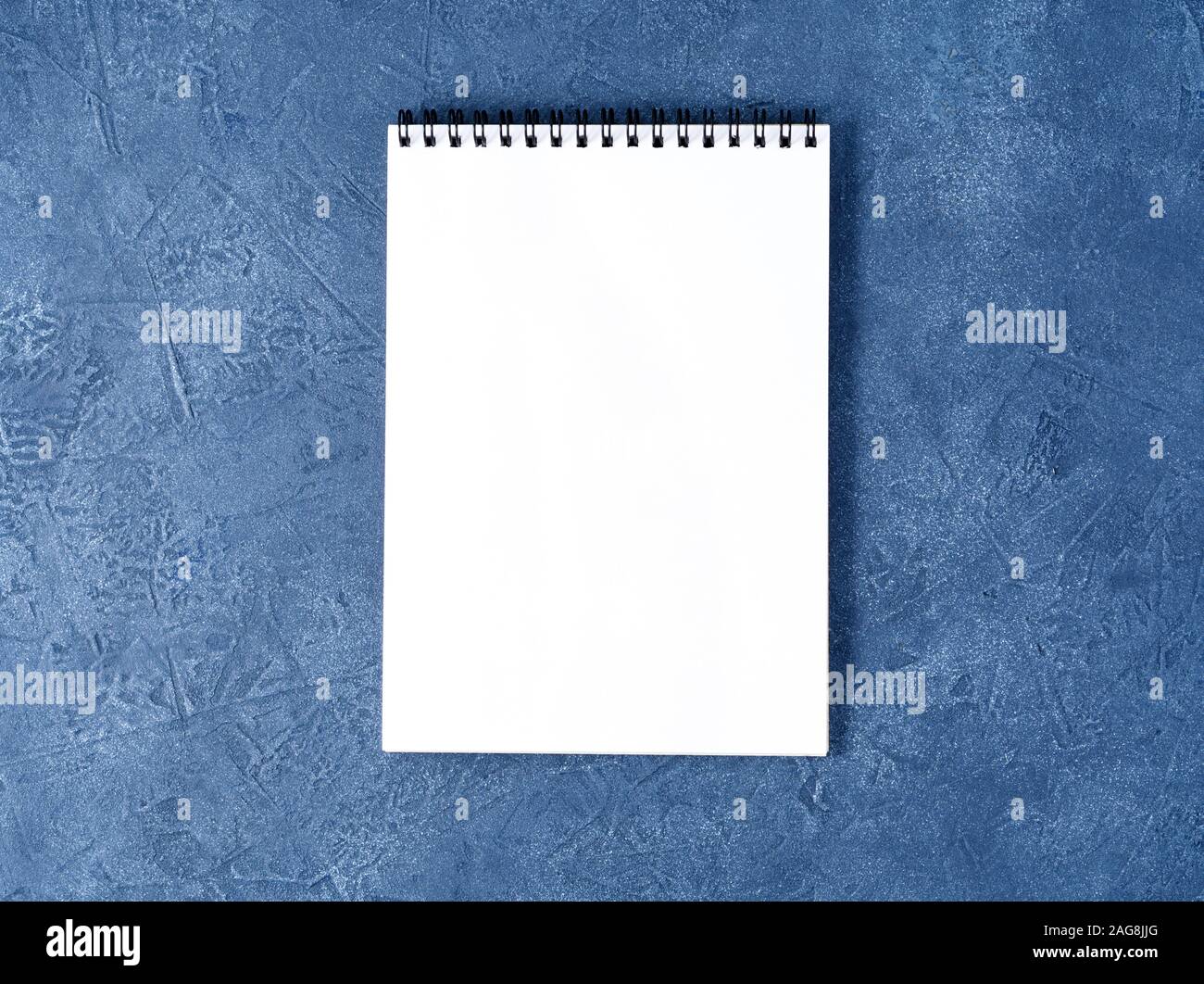 The open notepad with clean white page on a aged dark blue stone table ...