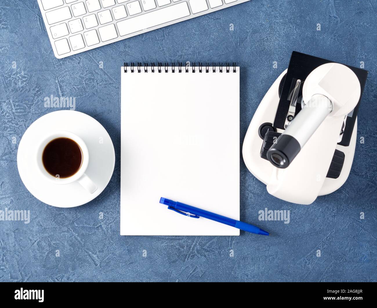 Top view of a dark blue desktop with microscope, notepad, computer ...