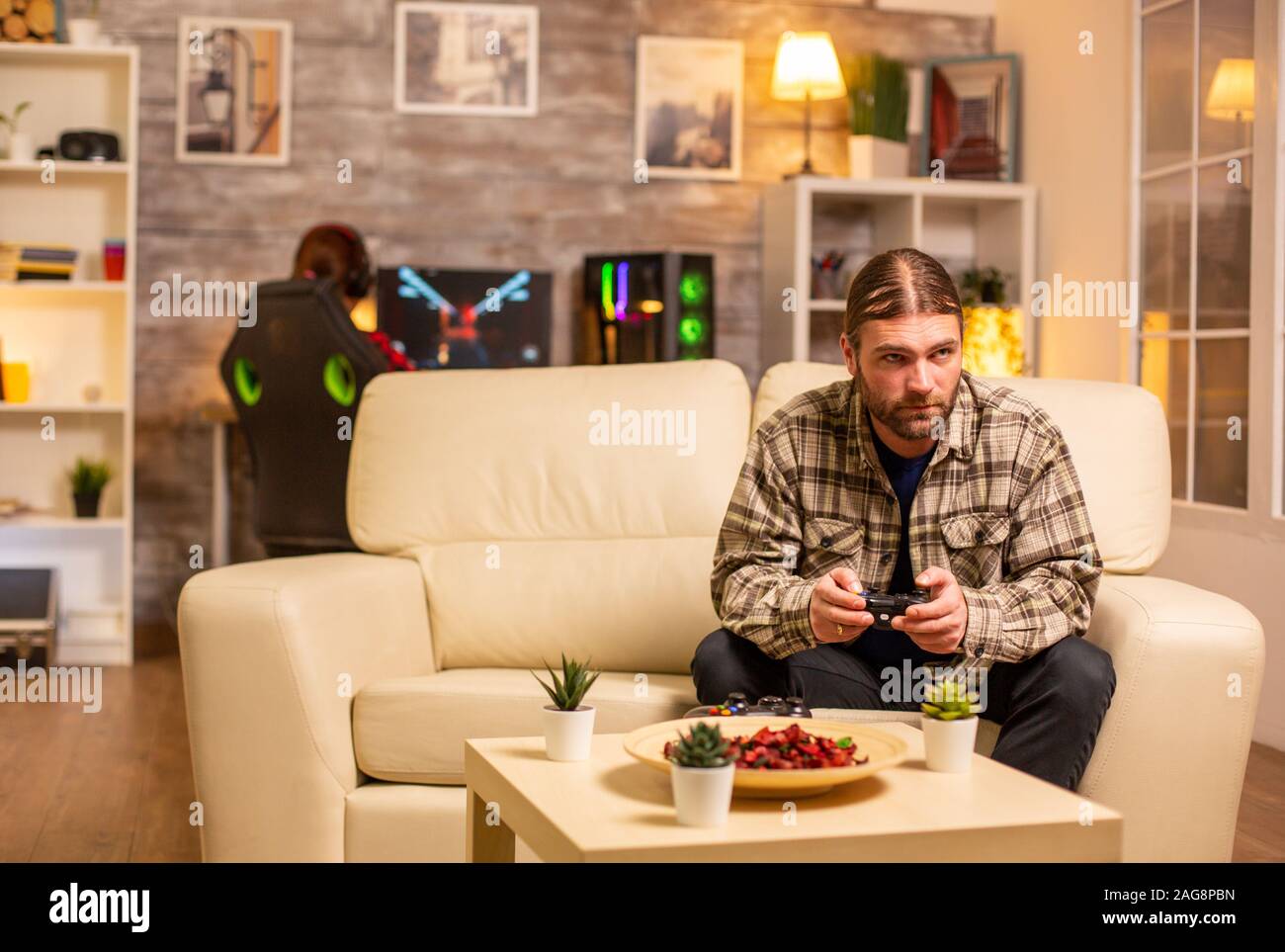 Male gamer playing video games on a console in the living room while ...