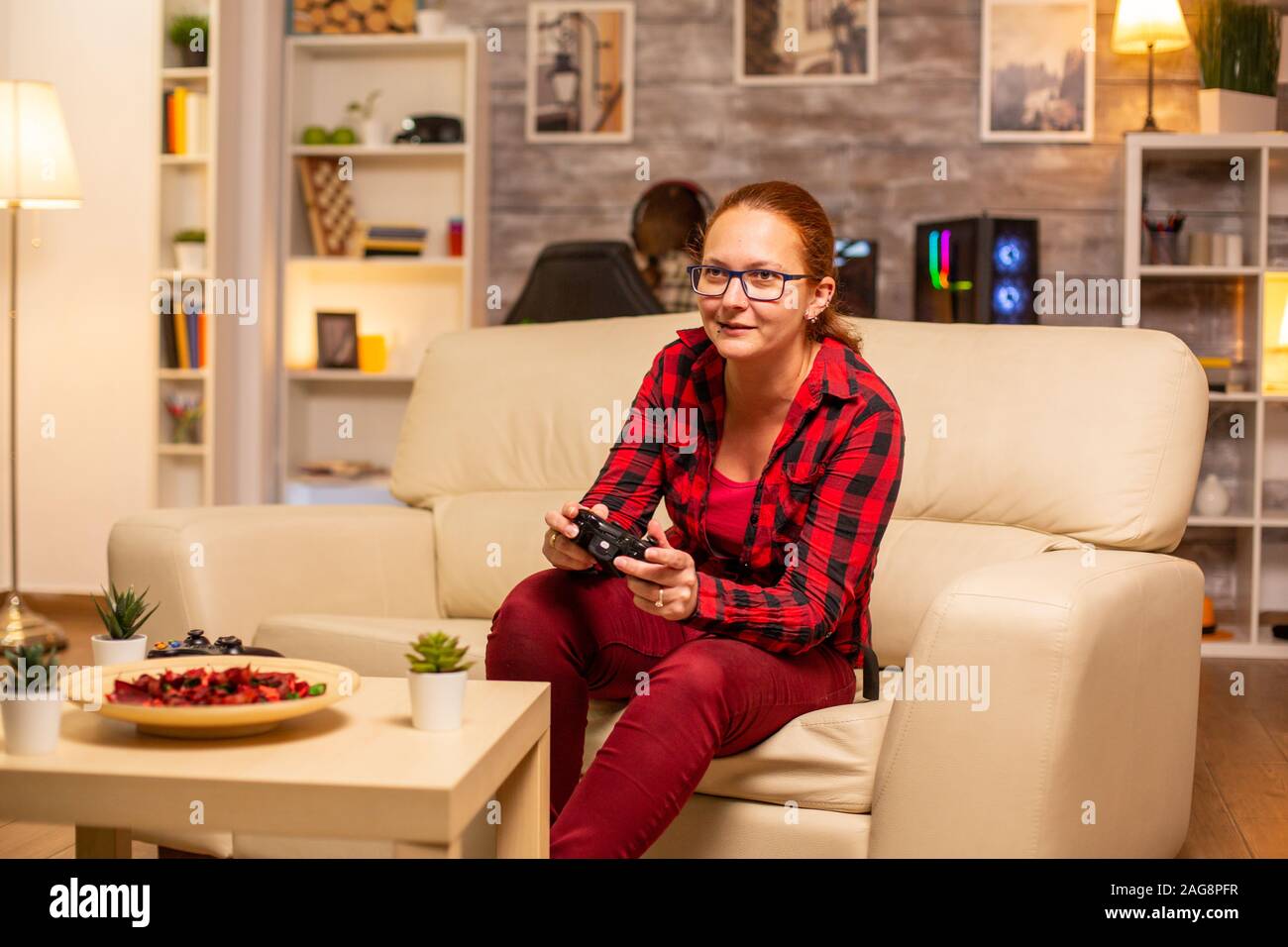 Woman gamer playing video games on the console in the living room late ...