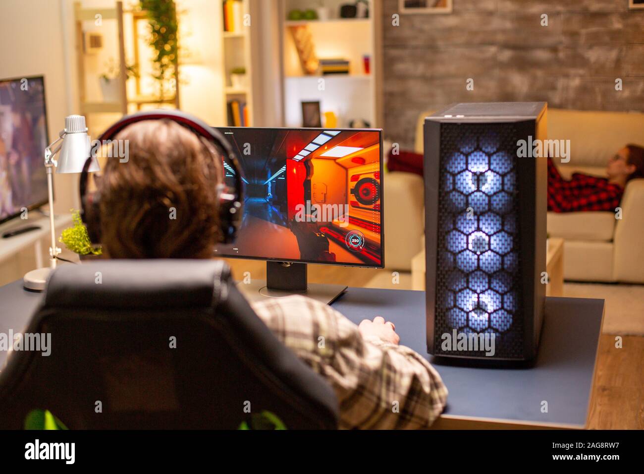 Back view of gamer male playing a shooter on his powerful PC computer ...