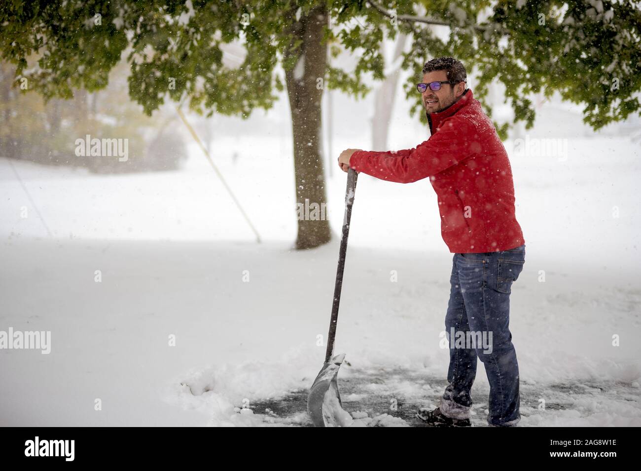 Male wearing a red jacket taking a rest from shoveling snow with a ...
