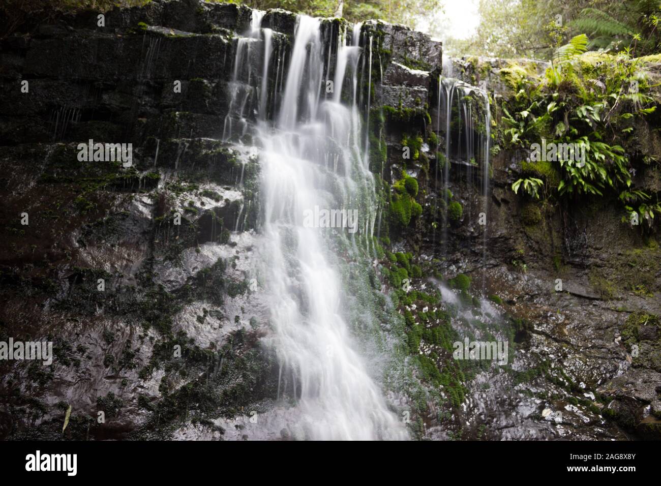 Low angle shot of a beautiful waterfall falling from the rock formation ...