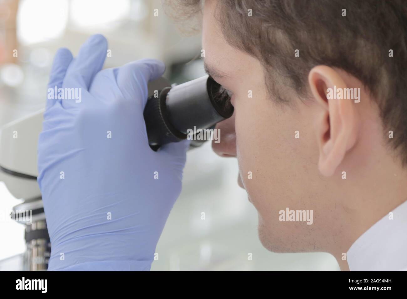 Youngmale male scientist looking through a microscope in a laboratory ...