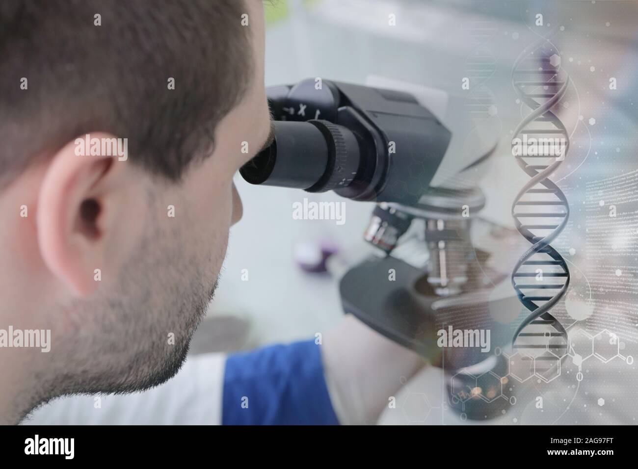 Young male male scientist looking through a microscope in a laboratory ...
