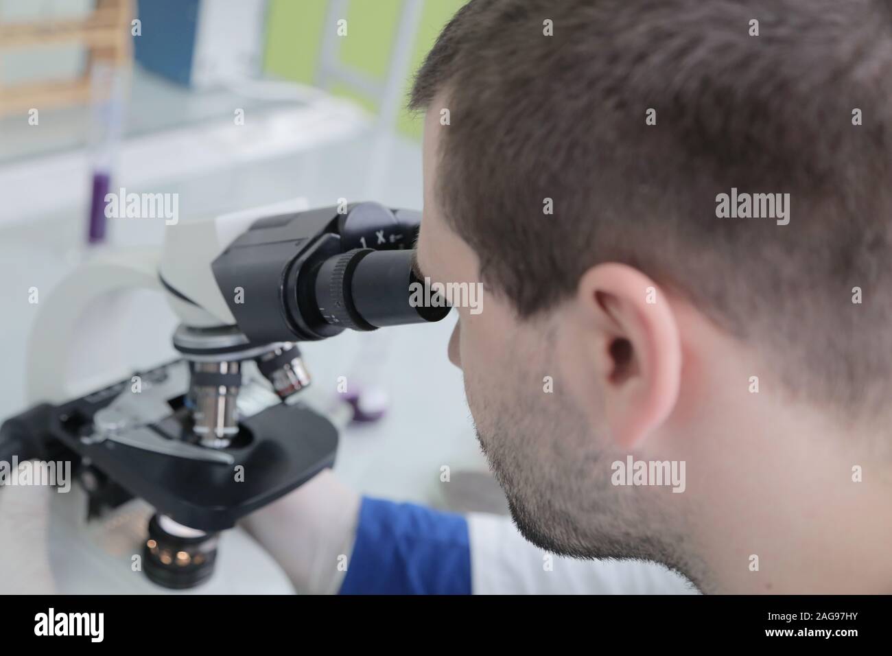Young male male scientist looking through a microscope in a laboratory ...