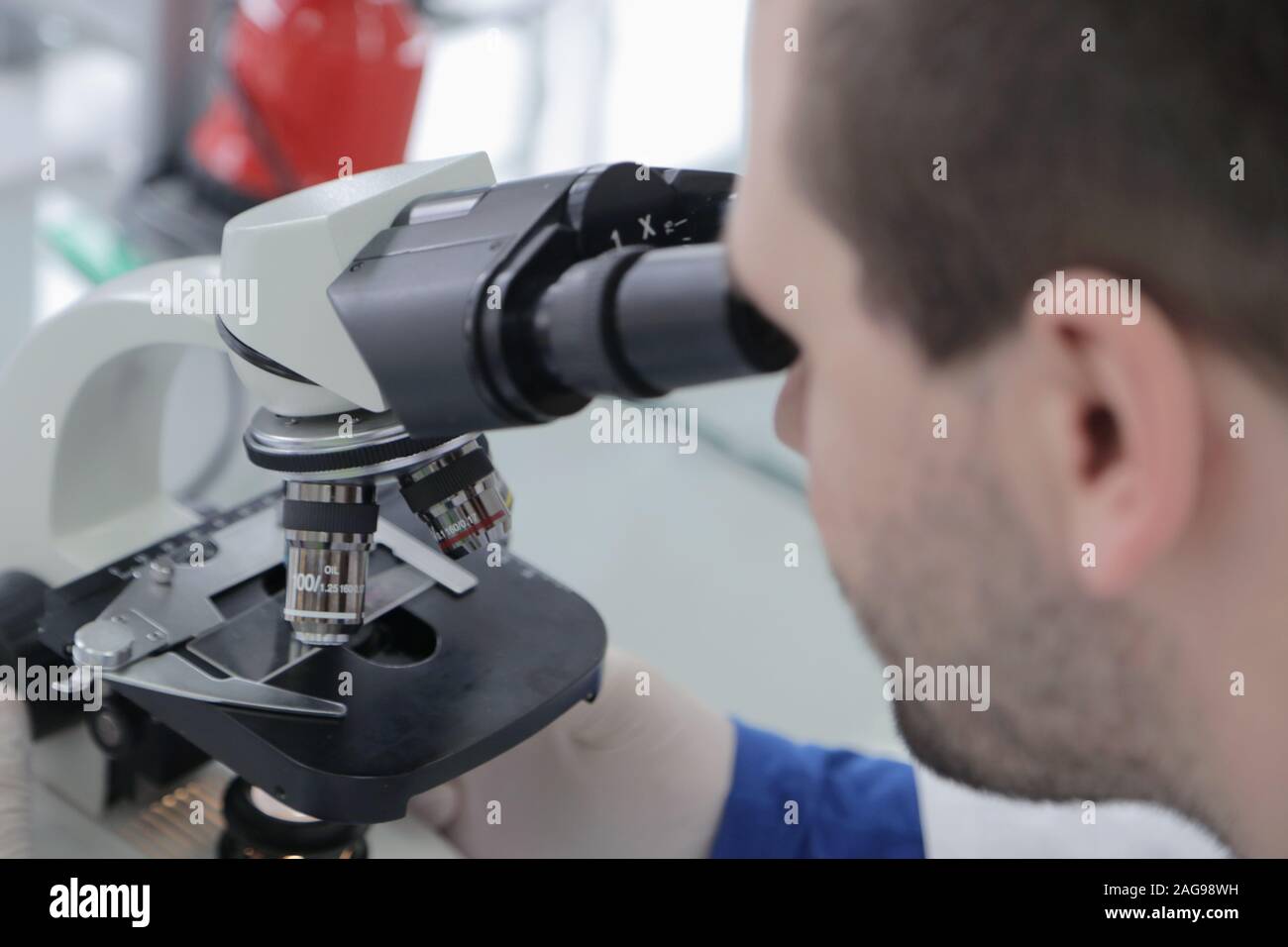 Young male male scientist looking through a microscope in a laboratory ...