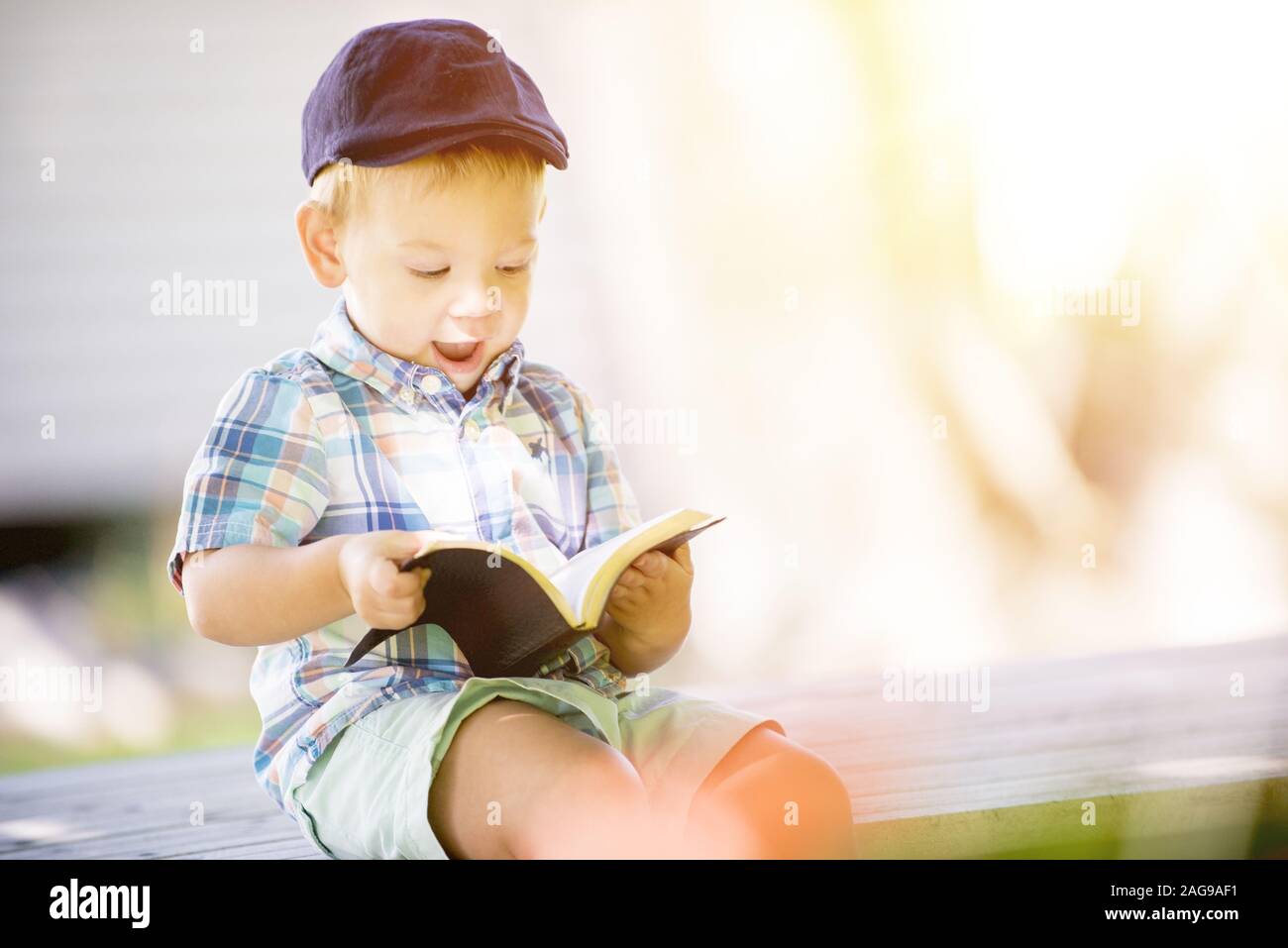 Closeup shot of a surprised child reading the bible with a blurred ...