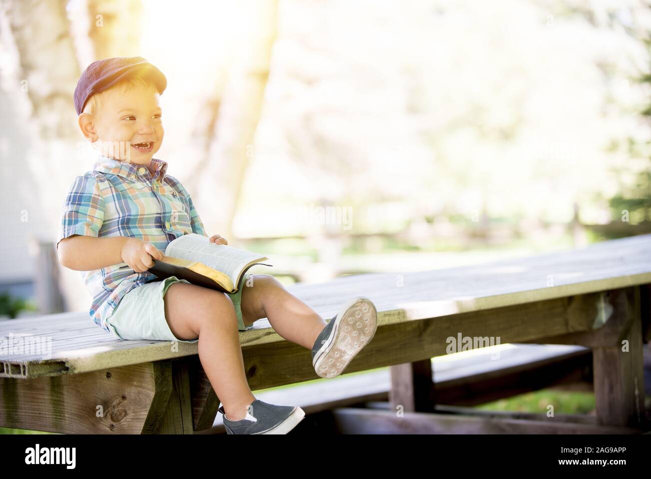 Closeup shot of a child happy child with an open bible on his laps and ...