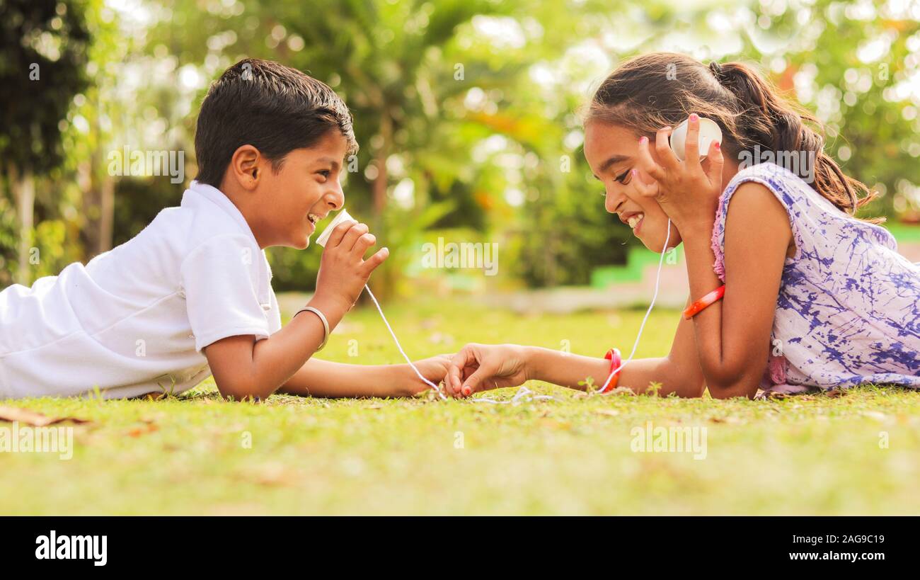 Two children having fun by playing with String Telephone at park during ...