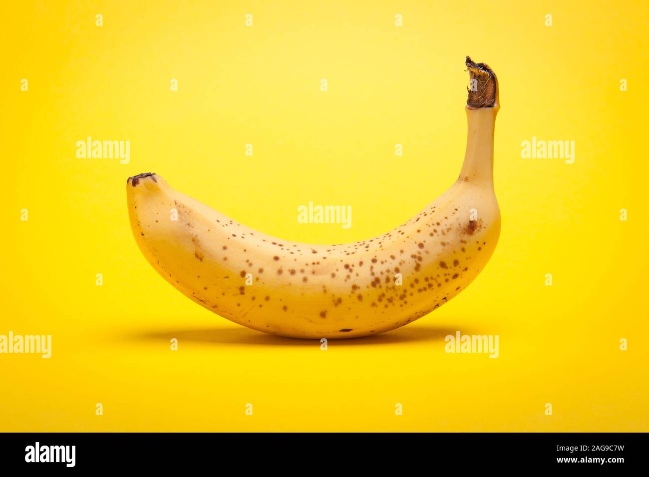 Overripe single banana isolated on yellow background with shadow ...