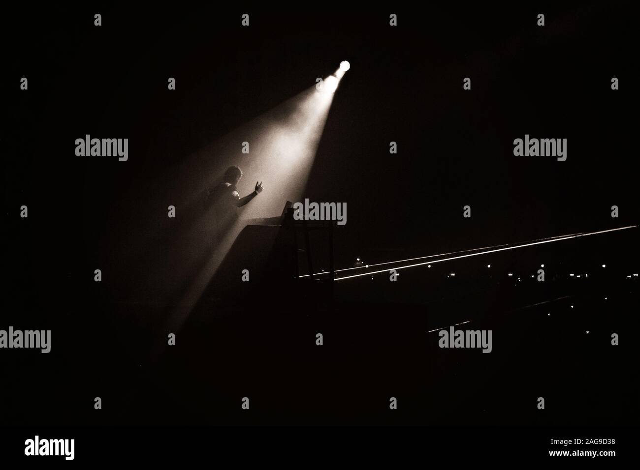 Gray scale shot of a person standing on the stage under the spotlight ...