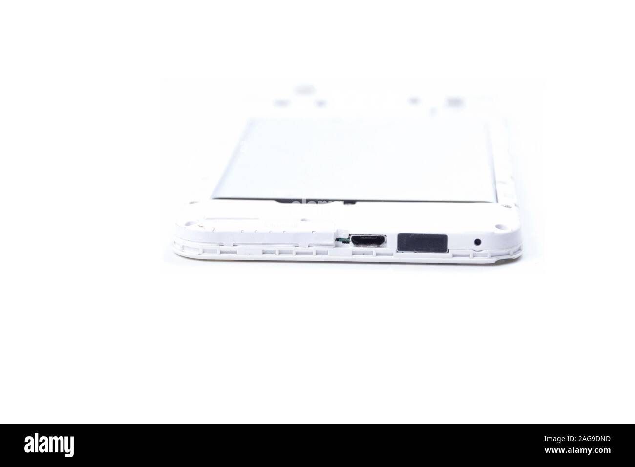 A cell phone with an open cover lies face down on a white background ...