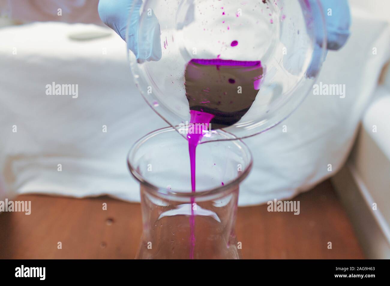 Person with blue gloves doing experiments with test tubes and purple ...