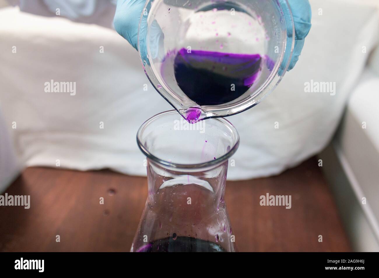 Person with blue gloves doing experiments with test tubes and purple ...