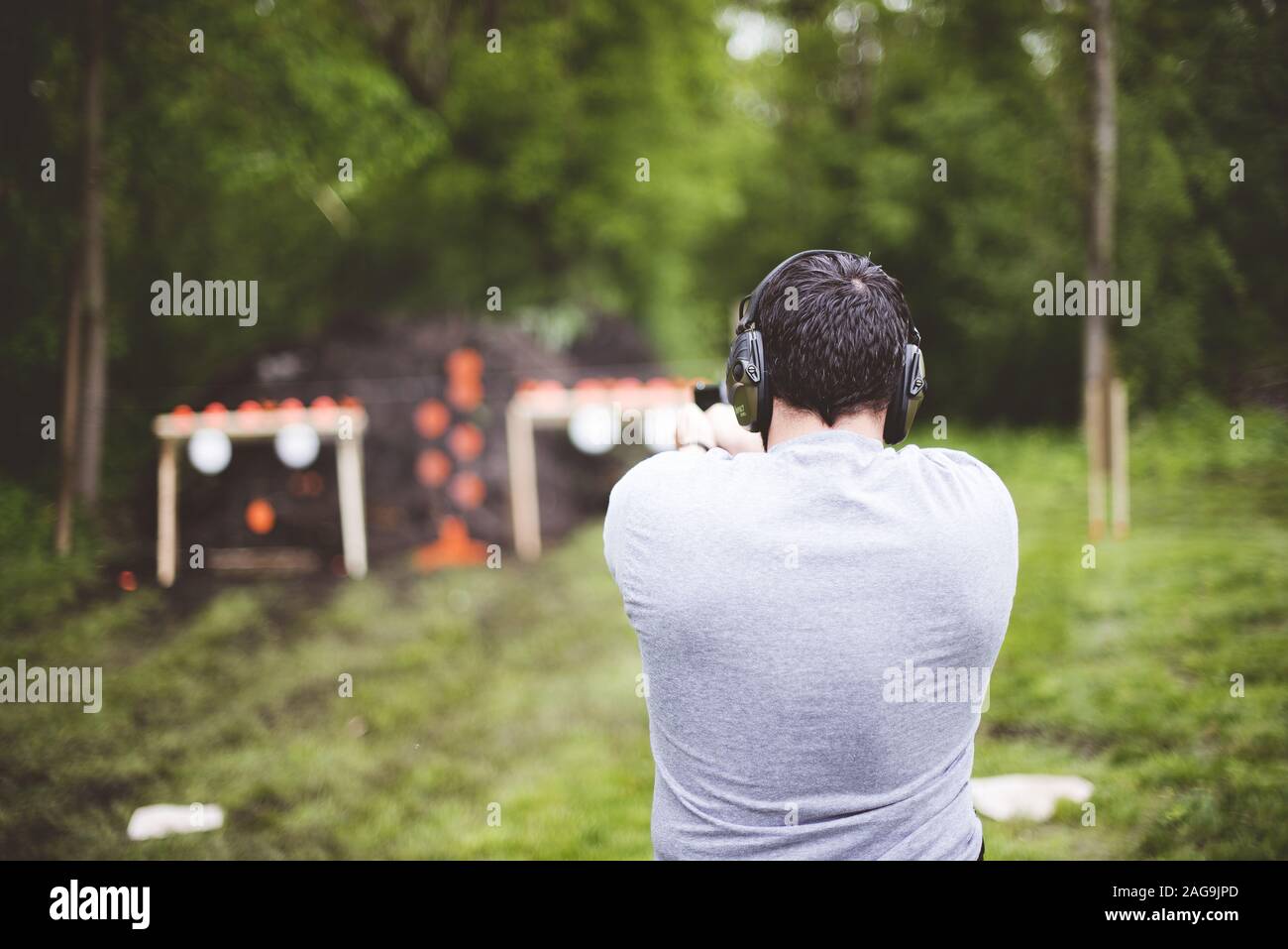 Shallow focus shot from behind of a male shooting a gun at a gun range ...